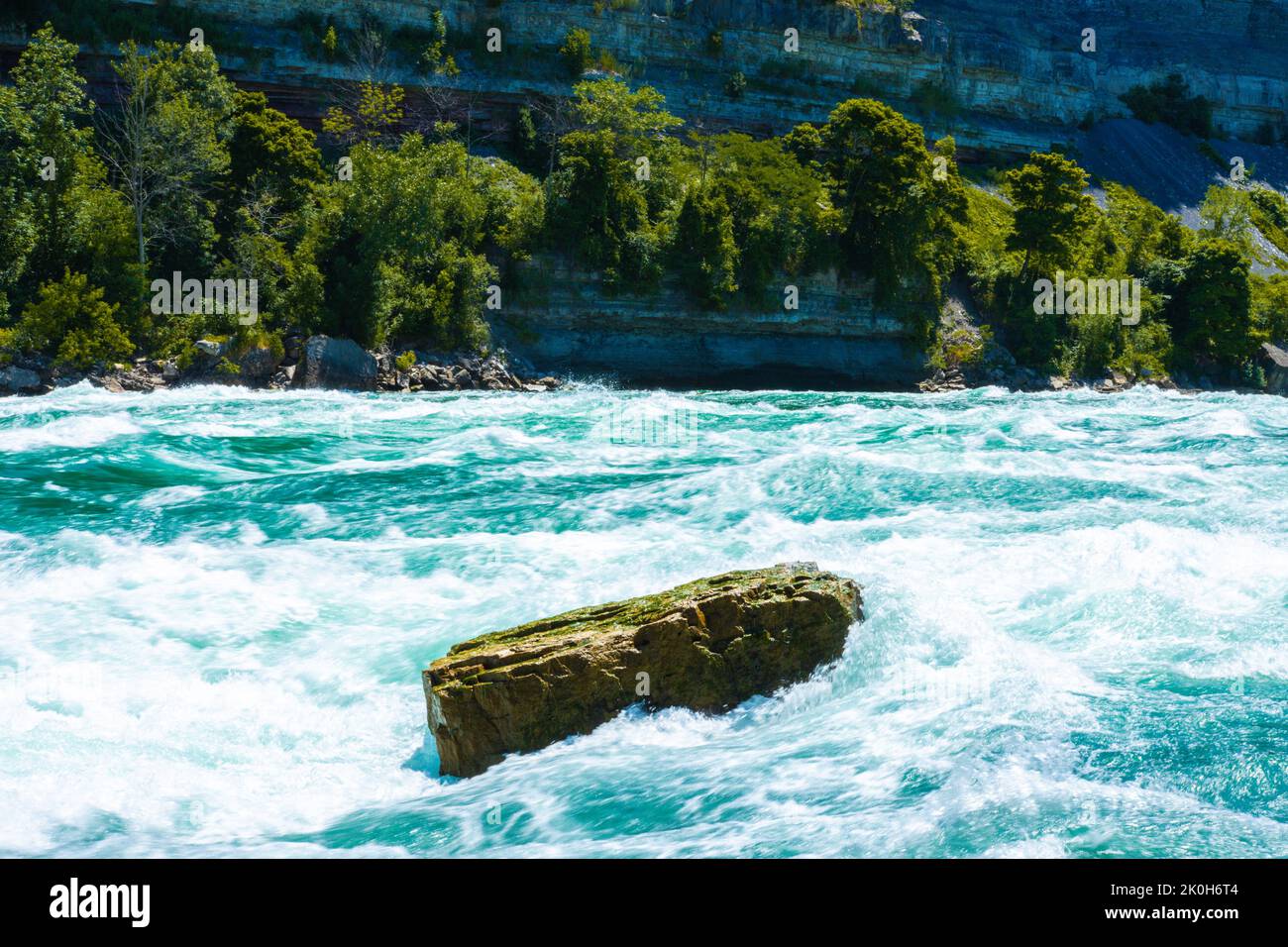 A scenic view of a blue crystal clear river with rocky shores in the ...
