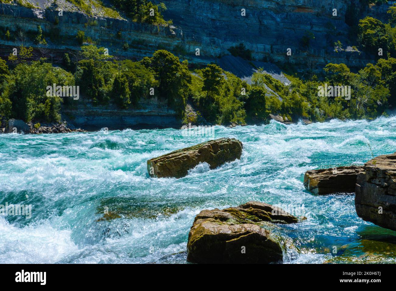 A scenic view of a blue crystal clear river with rocky shores in the ...