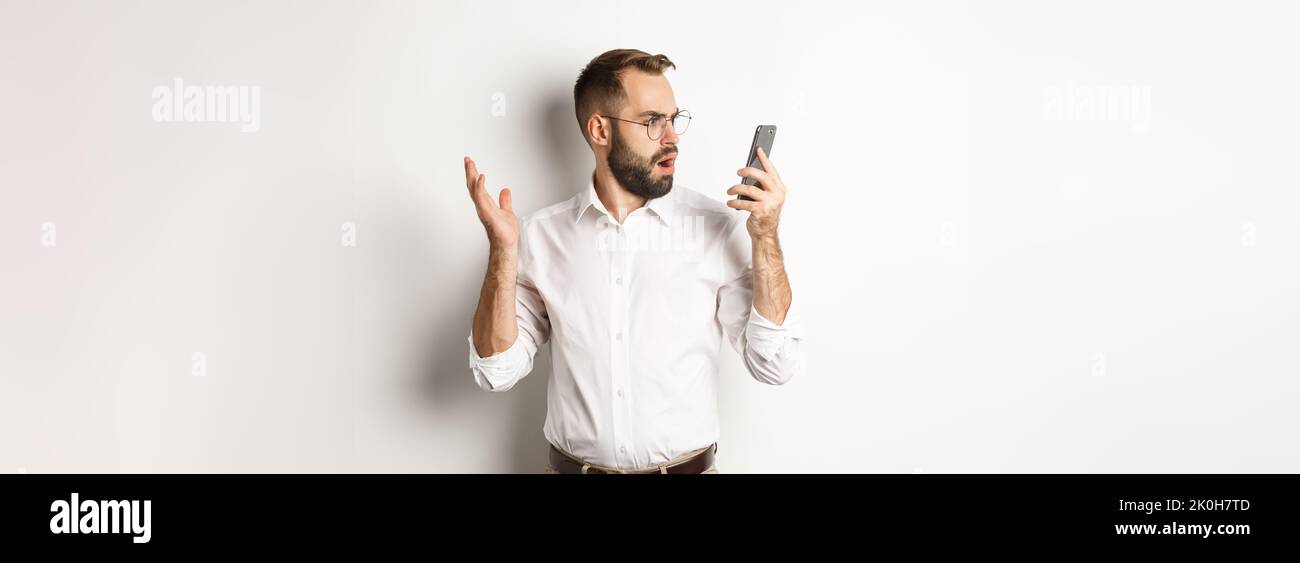 Man looking confused at mobile phone after conversation, standing ...