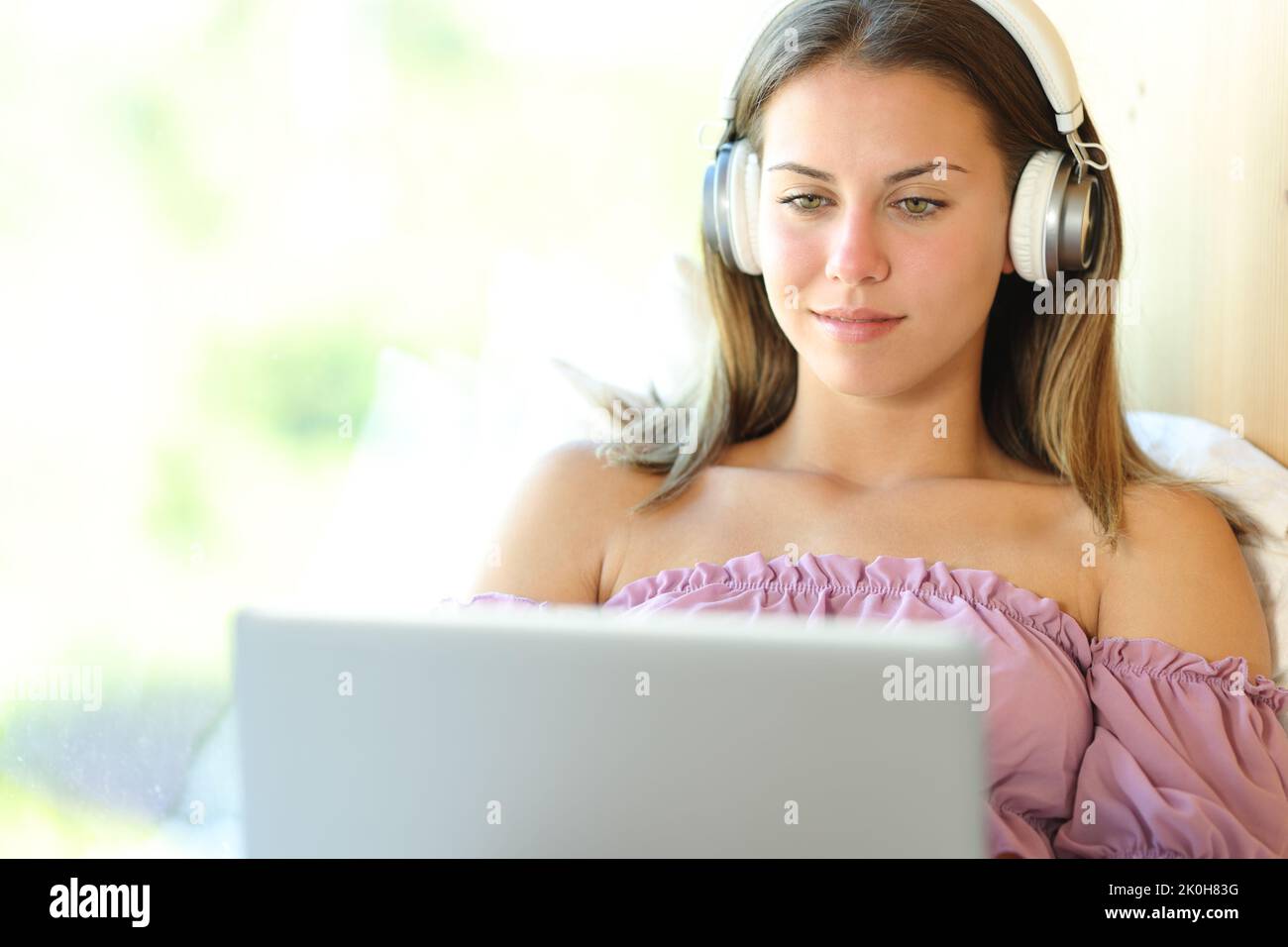 Front view portrait of a young woman watching media on laptop at home ...