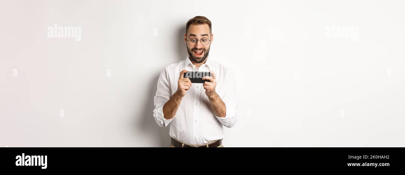 Man looking excited and surprised at mobile phone, holding smartphone ...