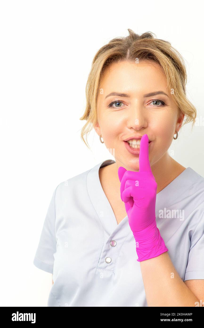 Young Beautiful Caucasian Woman Doctor Beautician Doing Silent Gesture Pressing His Index