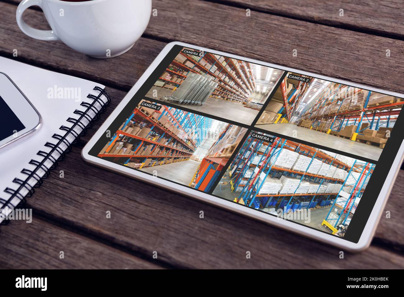 Tablet with views of warehouse from security cameras on screen lying on ...