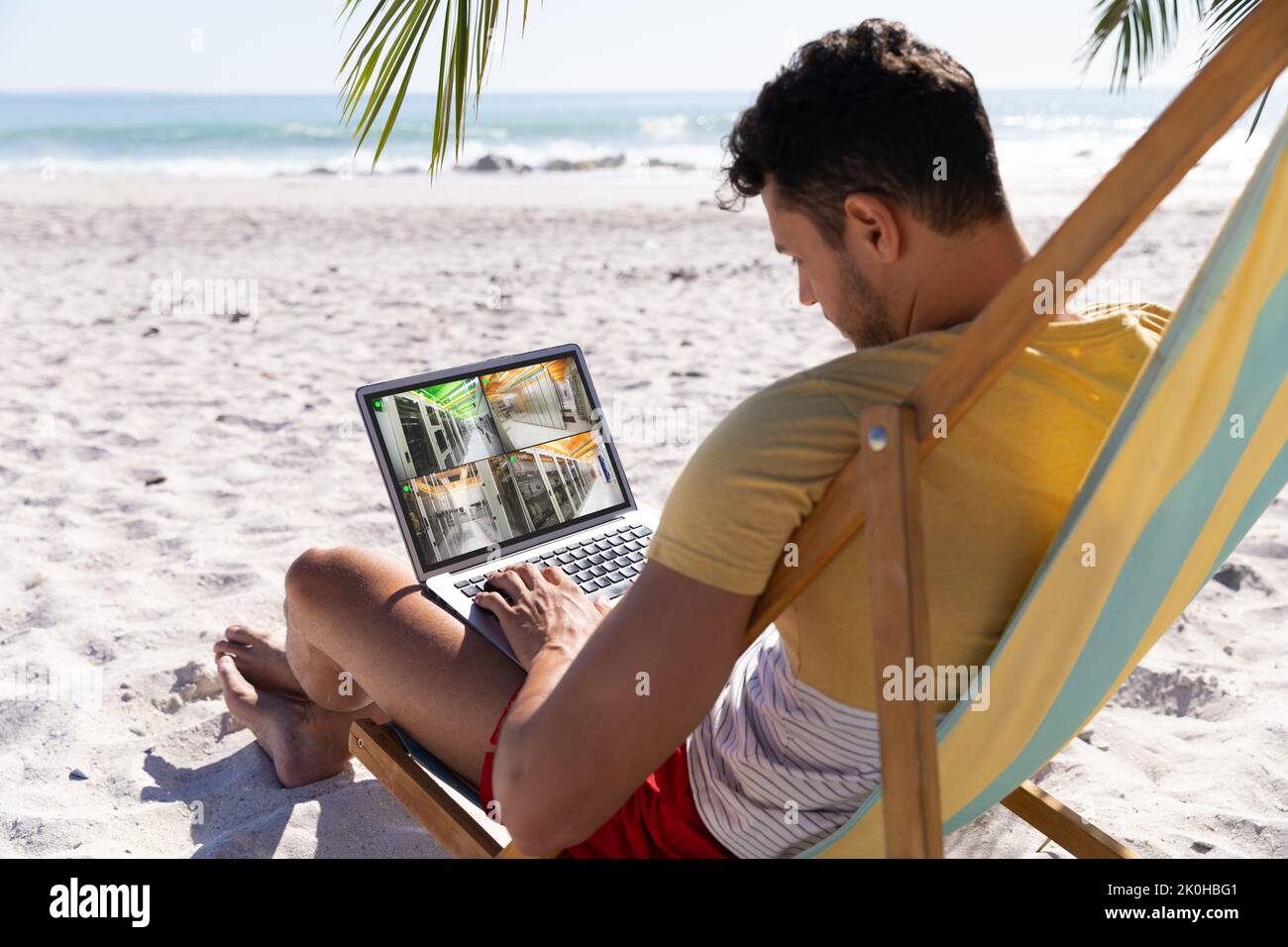 Caucasian man on holiday using laptop with views of server rooms from ...