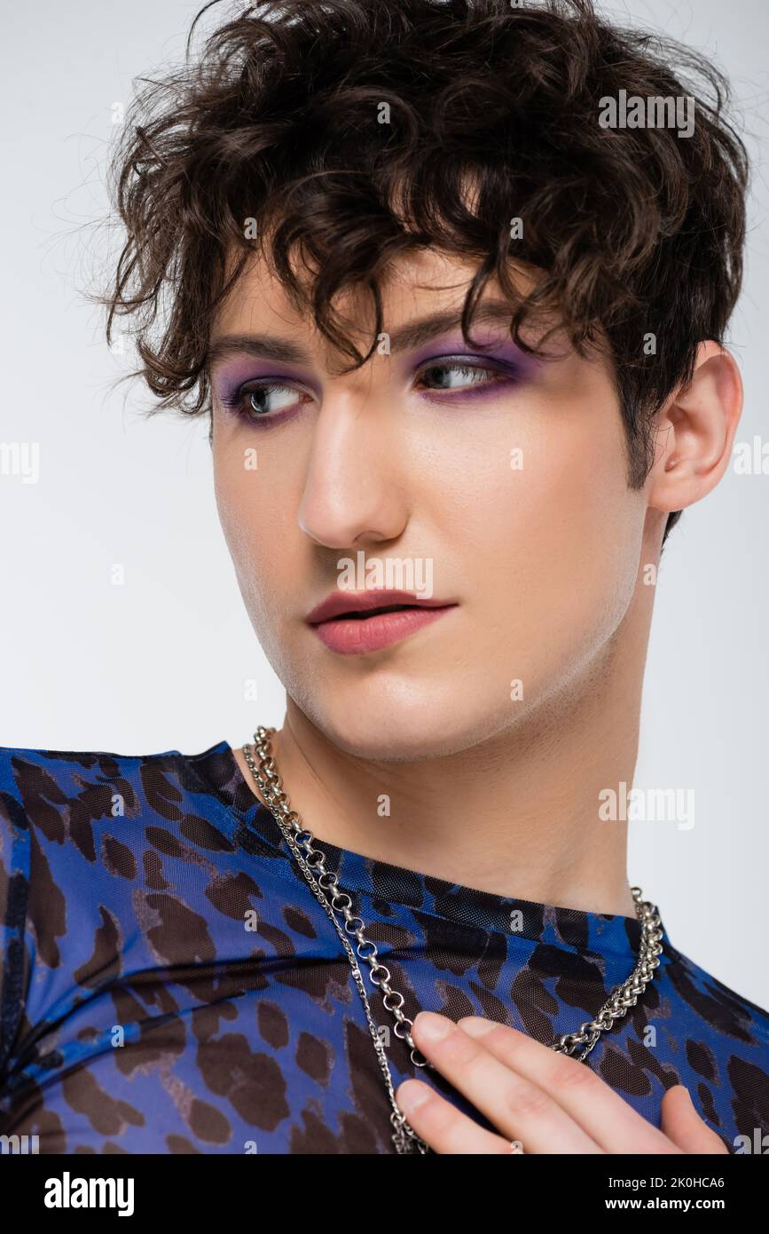 portrait of queer person with makeup and wavy hair isolated on grey ...