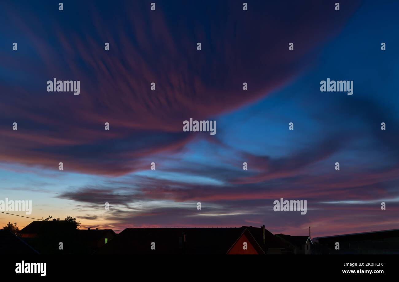 Abstract cloud on sky above house roofs, cloud pattern in long exposure ...