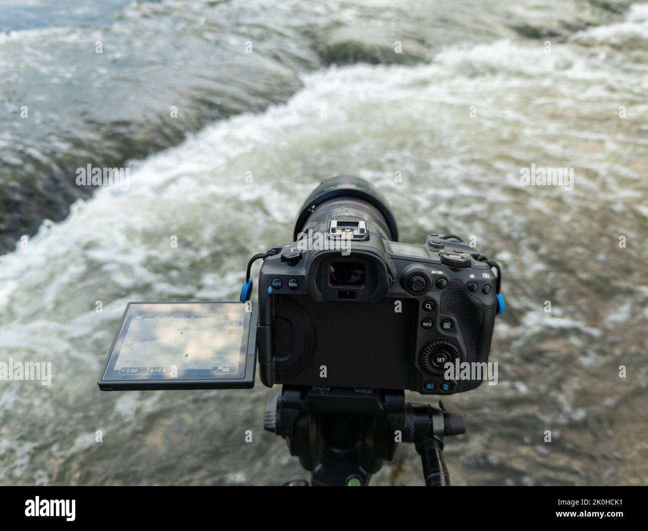 modern black digital mirrorless camera with flip-screen on tripod ...