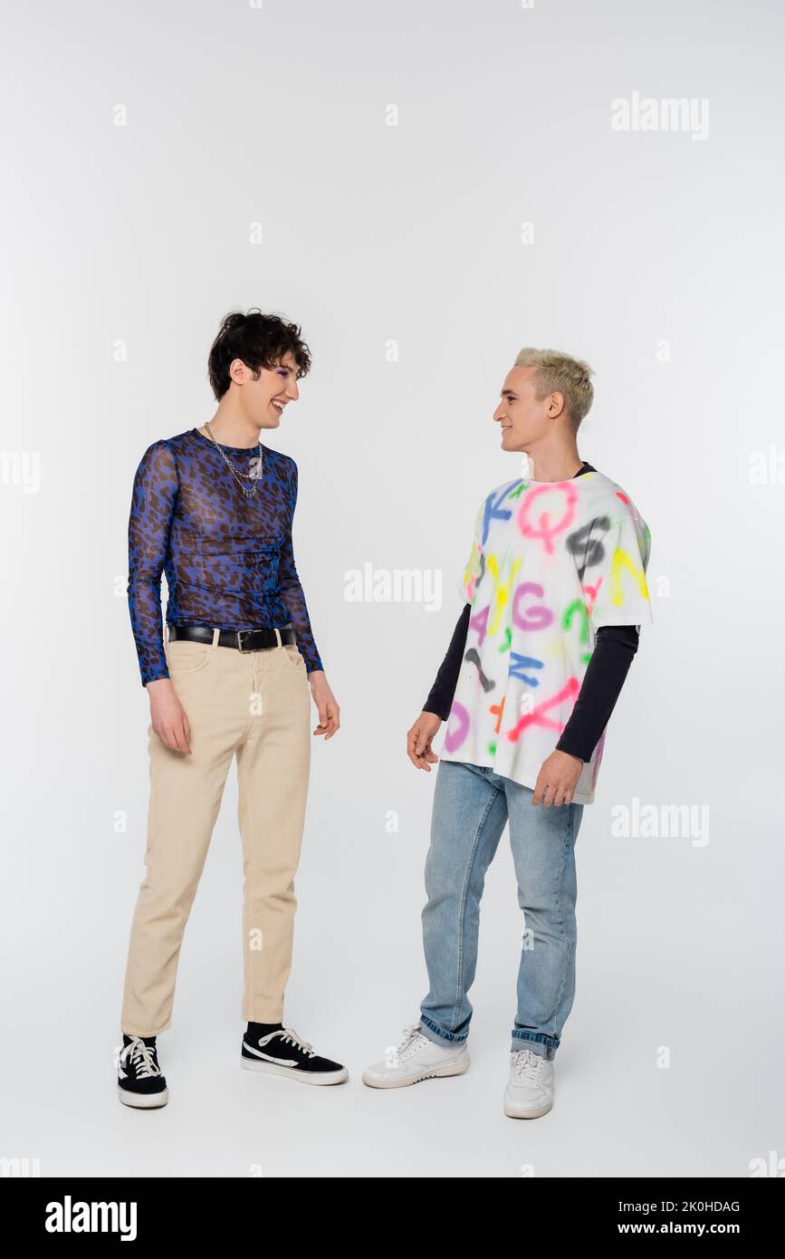 full length of happy gay man and queer person looking at each other on ...