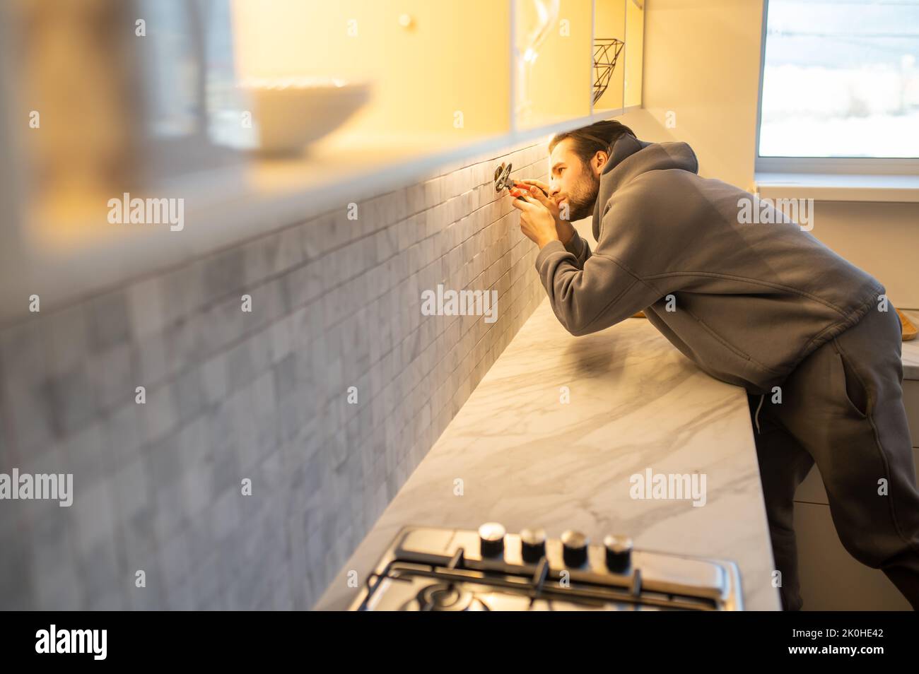 Man installing the power socket on the kitchen wall Stock Photo - Alamy