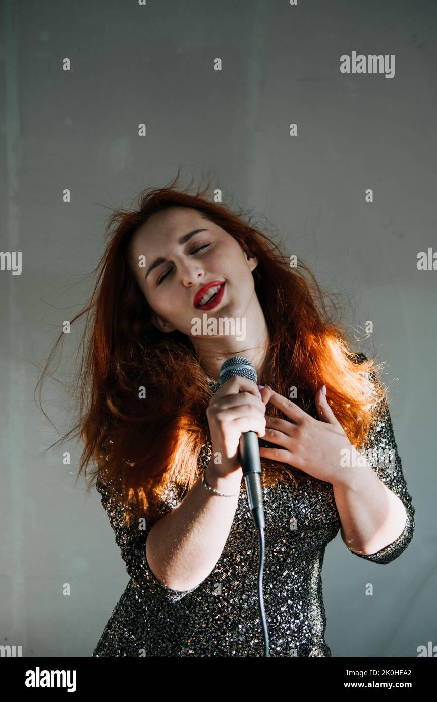 Portrait of redhead female singer woman in sparkly evening dress ...