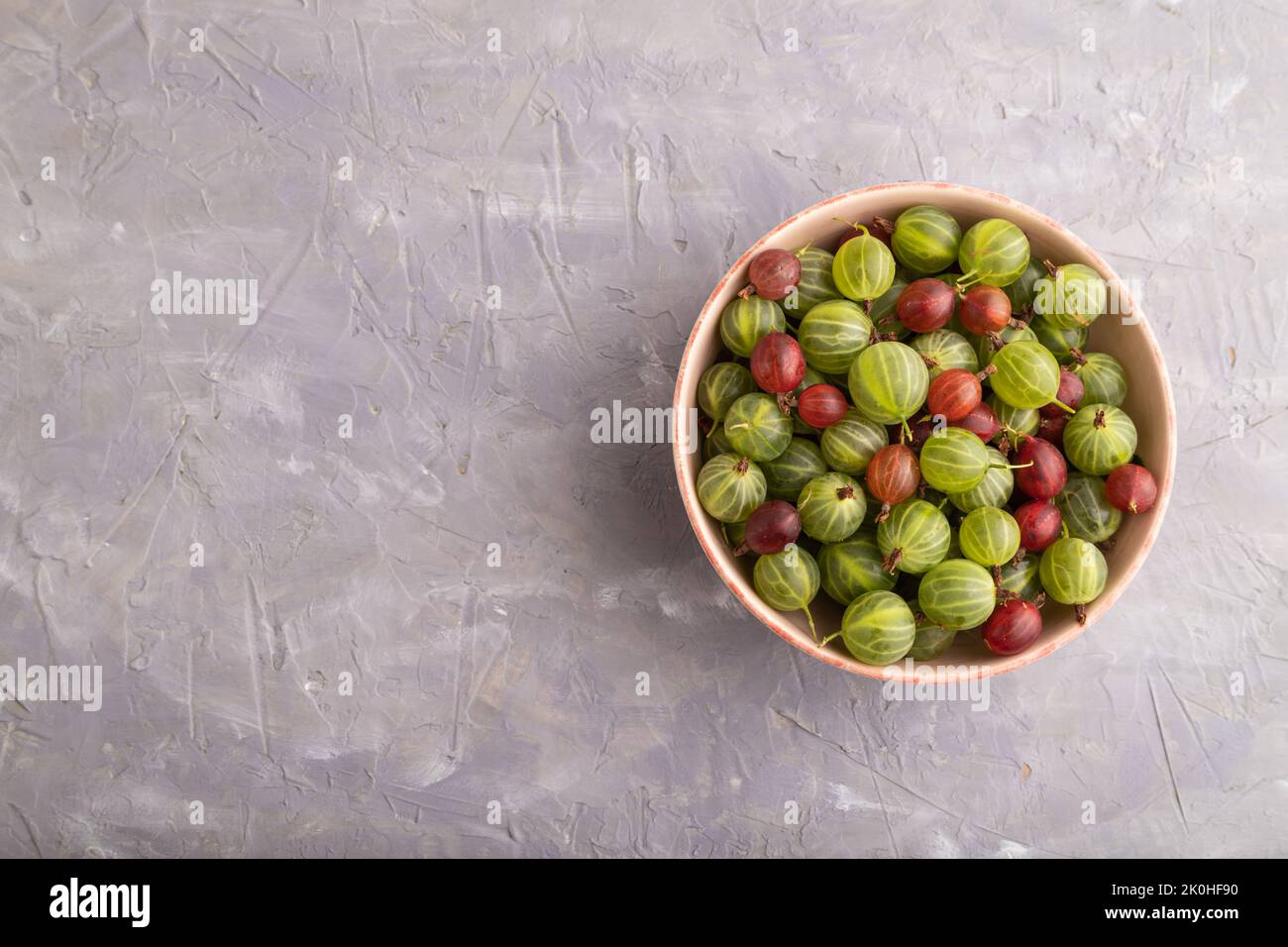 Fresh red and green gooseberry in ceramic bowl on gray concrete ...