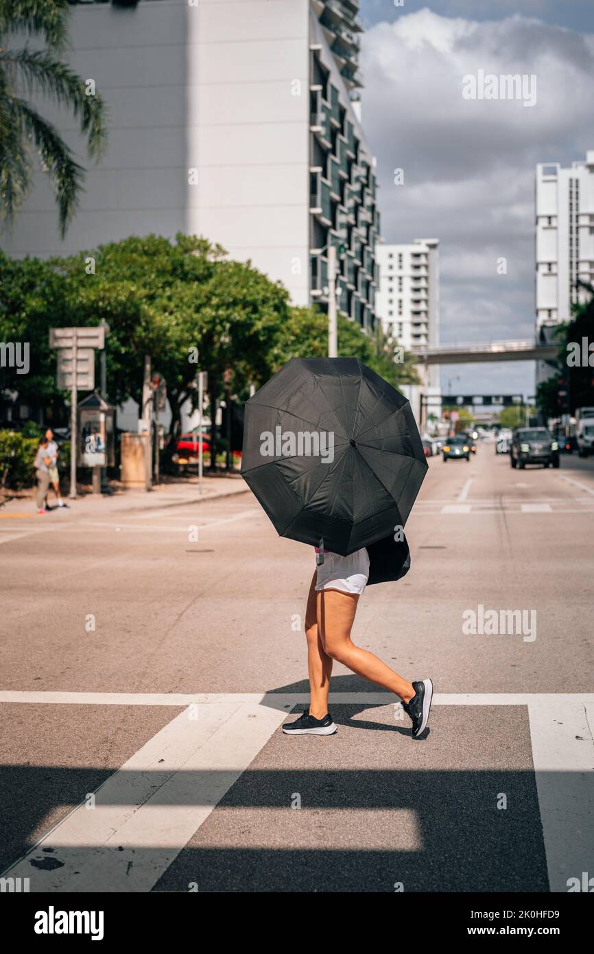 The vertical view of the female hiding behind a black umbrella while ...