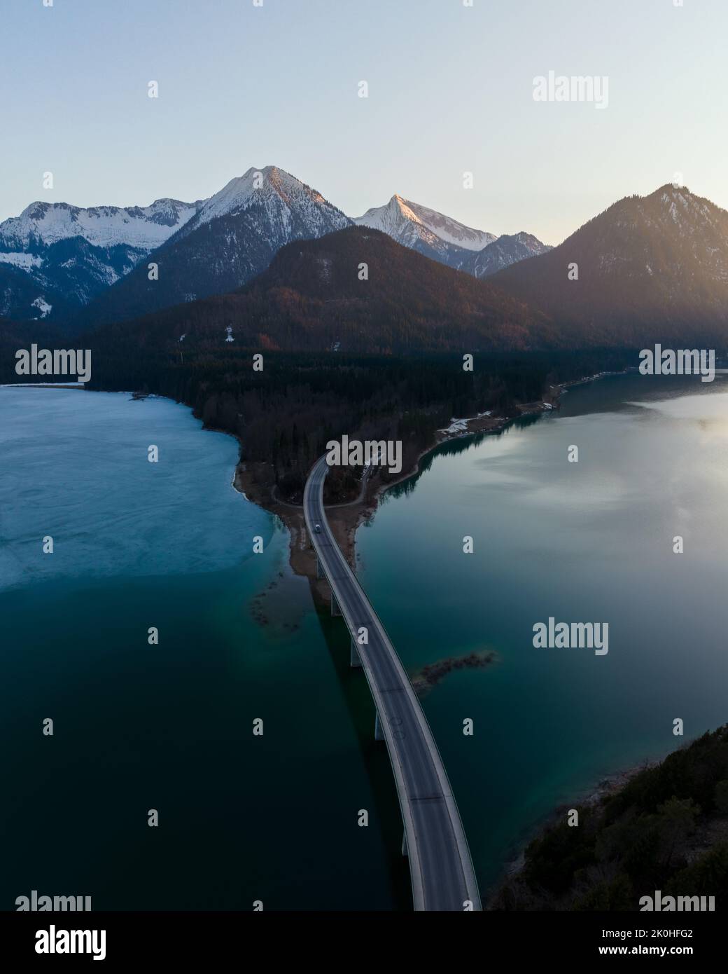 A vertical shot of a bridge with an asphalt road crossing over a lake ...