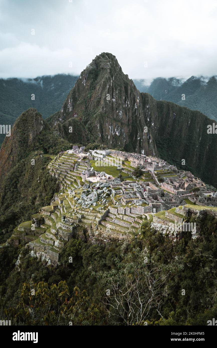 A vertical shot of a Machu Picchu landscape at sunset with a cloudy sky ...