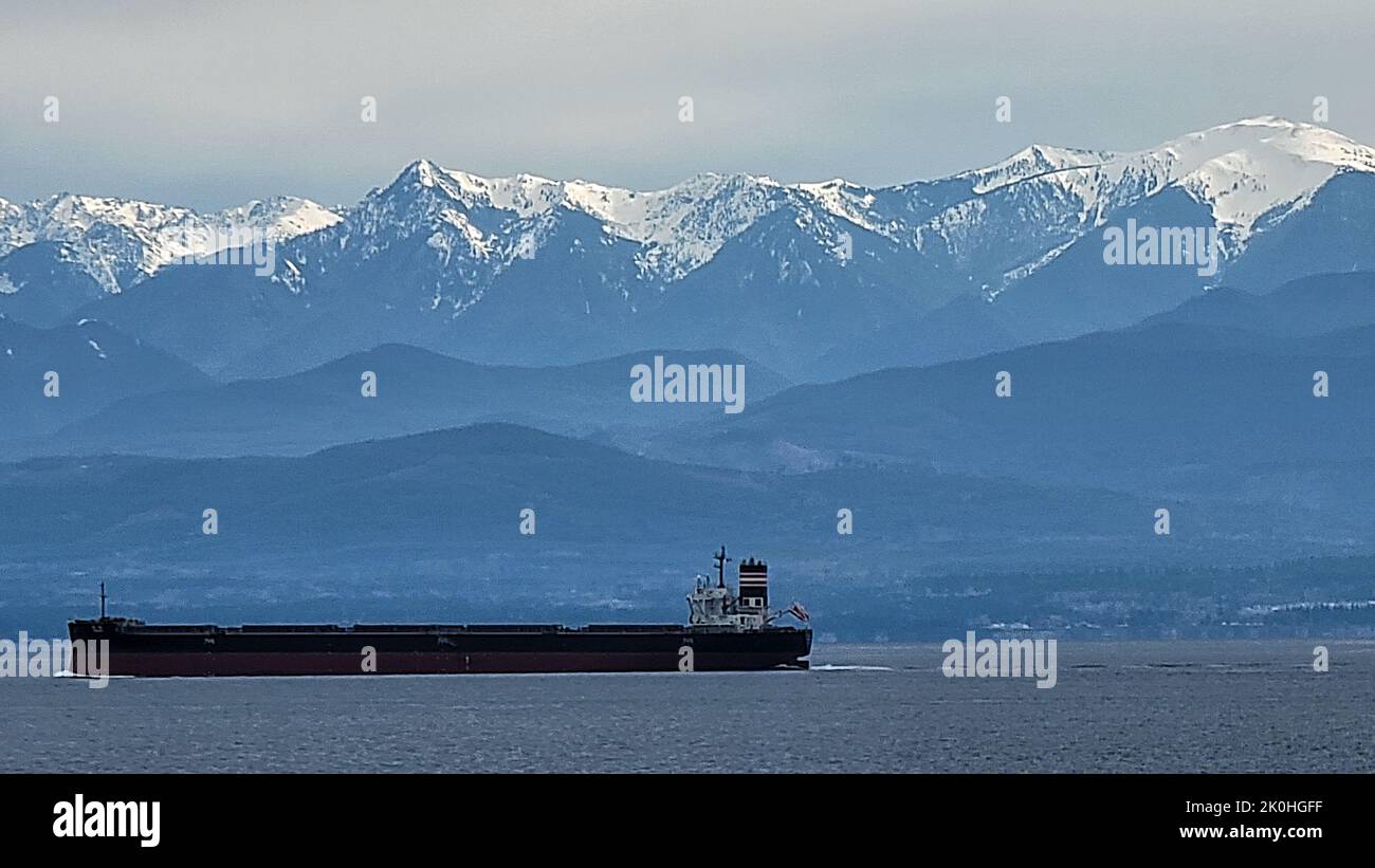 A large tanker driving on the lake against the mountain range ...