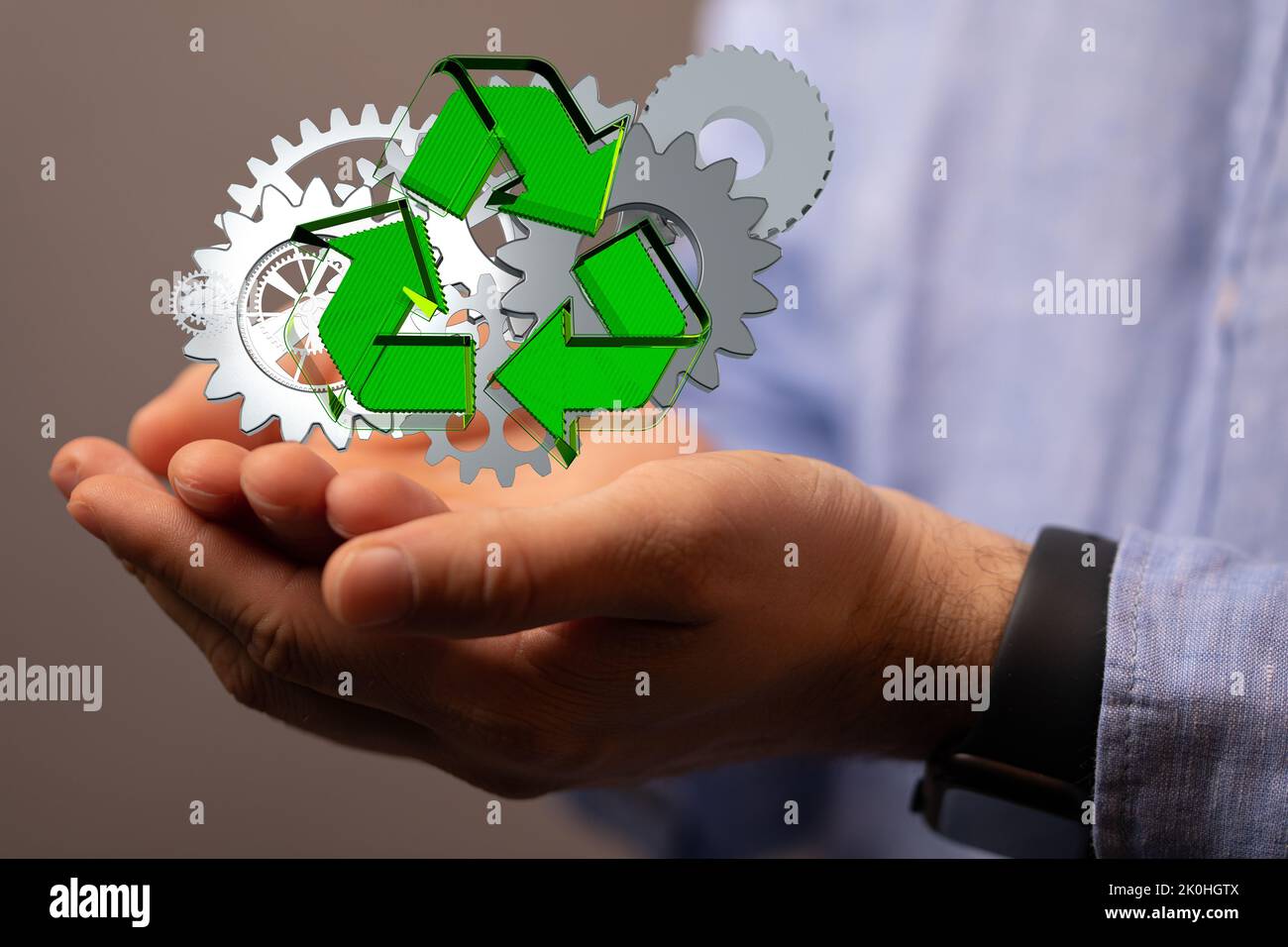 A person holding an illustrative recycle symbol and gears in his hands ...