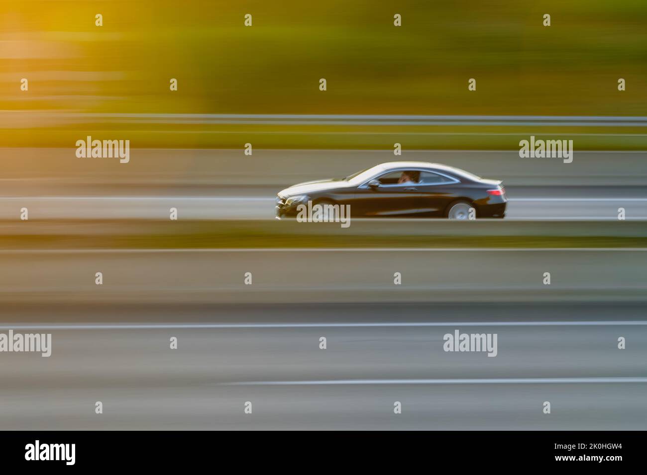 A black car speeding in motion on a highway on a sunny day Stock Photo ...