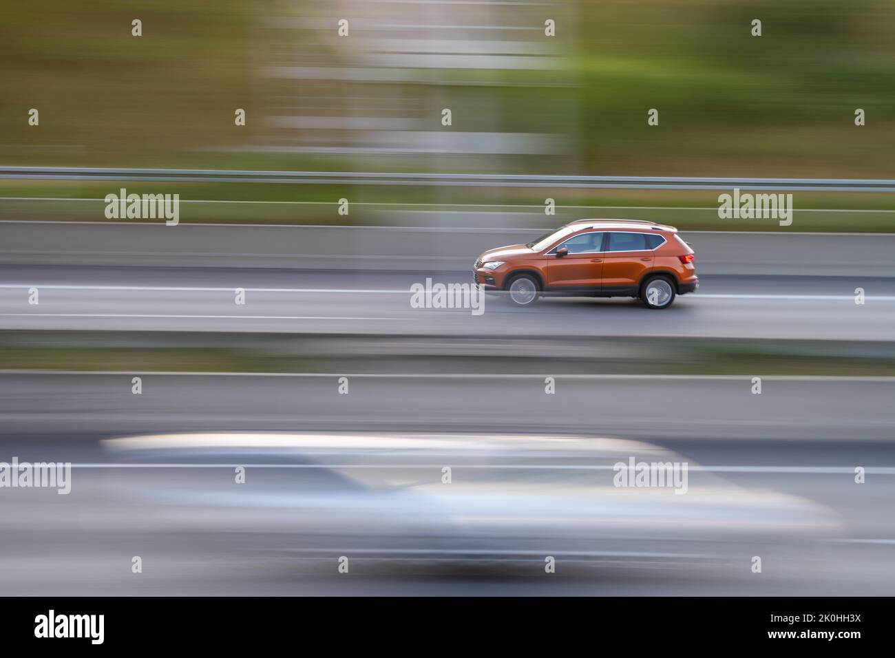 An orange car speeding in motion on a highway on a sunny day Stock ...