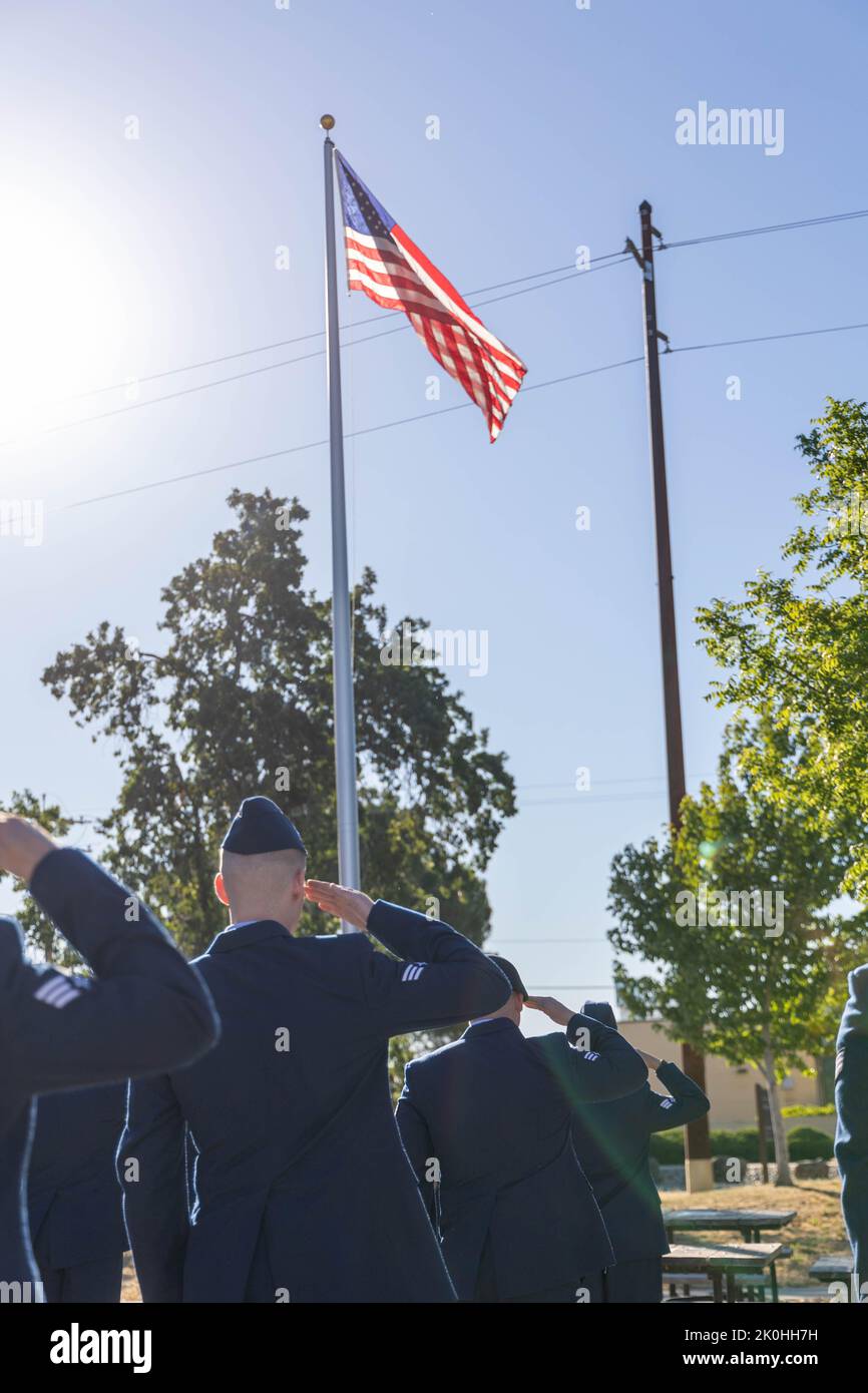 A vertical shot of servicemen in uniforms saluting the flag of the ...