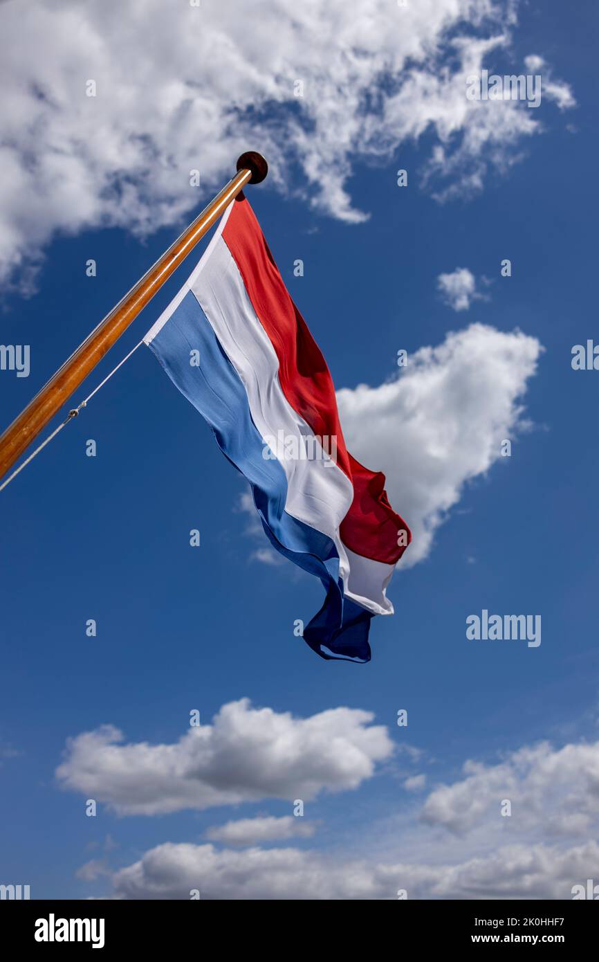 Brightly lit tricolor of Dutch national flag blowing in a strong wind ...
