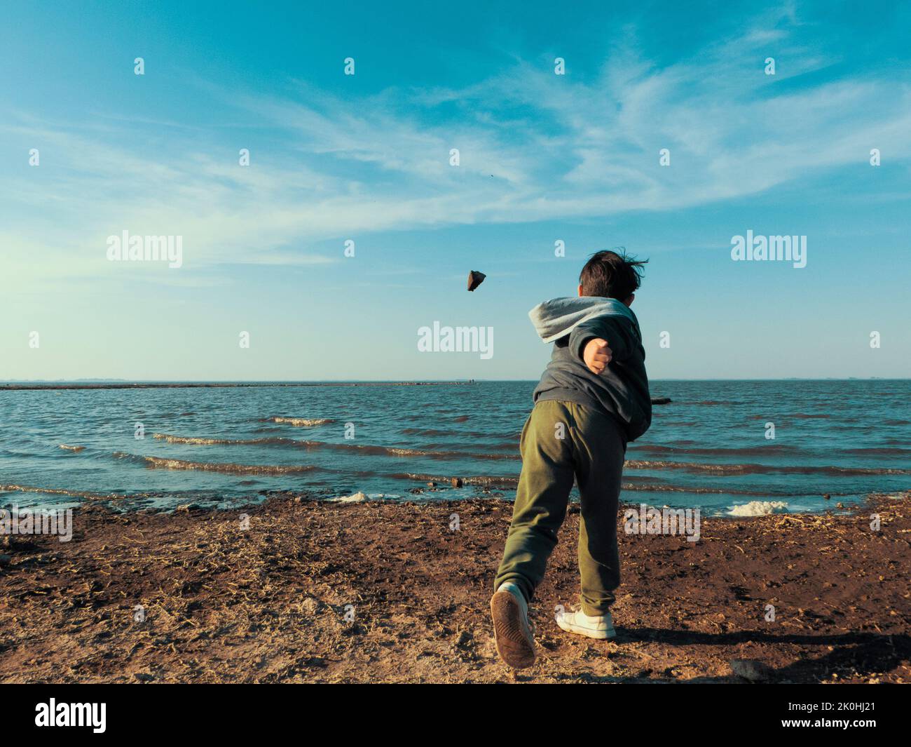 A little child throwing a stone into the sea Stock Photo - Alamy