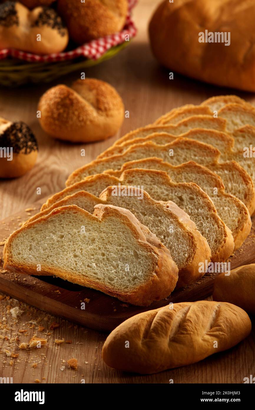 A vertical French bread baguette cut on vintage wooden bread board ...