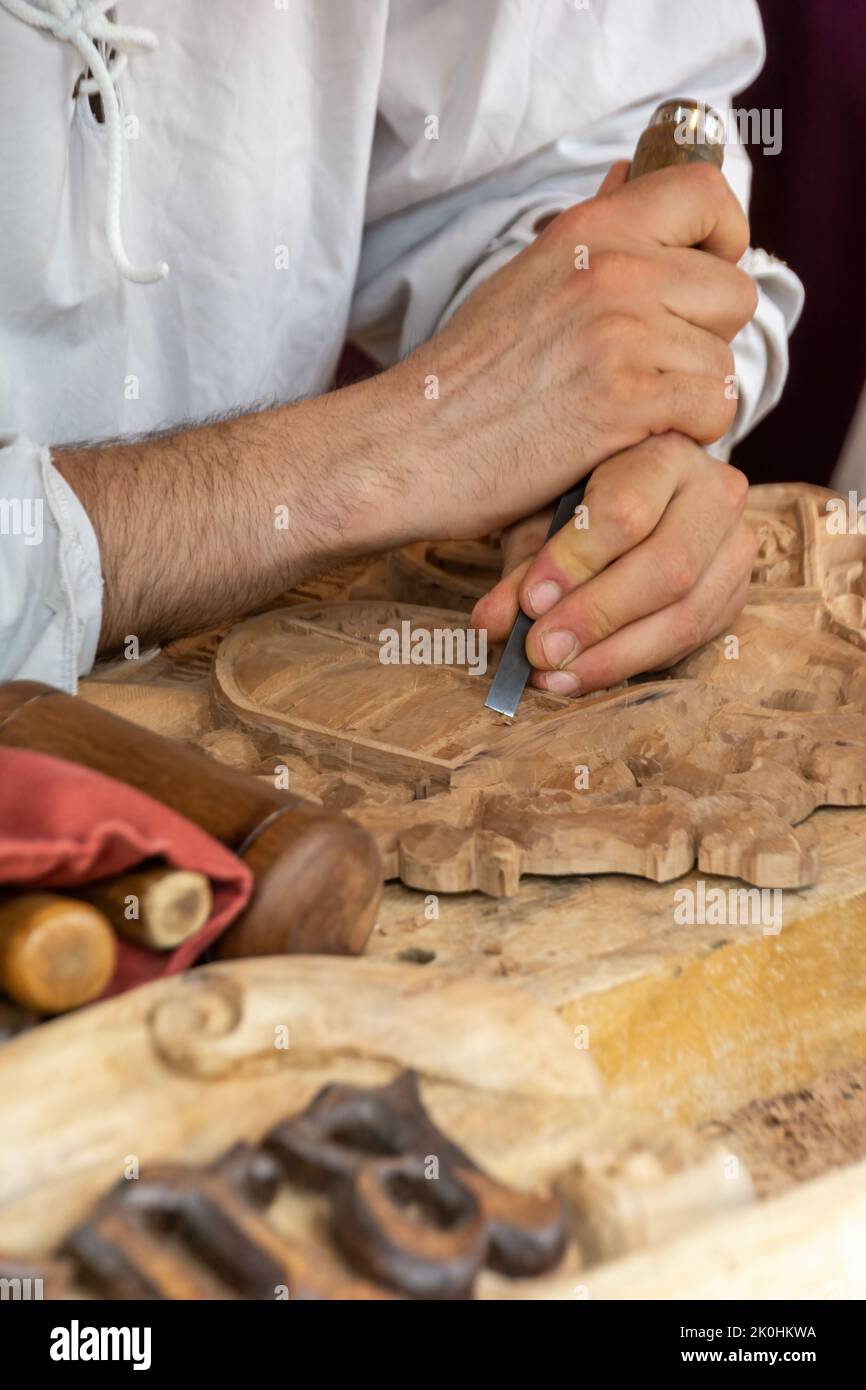 A vertical shot of a carpenter craftsman carving a wooden shield by ...