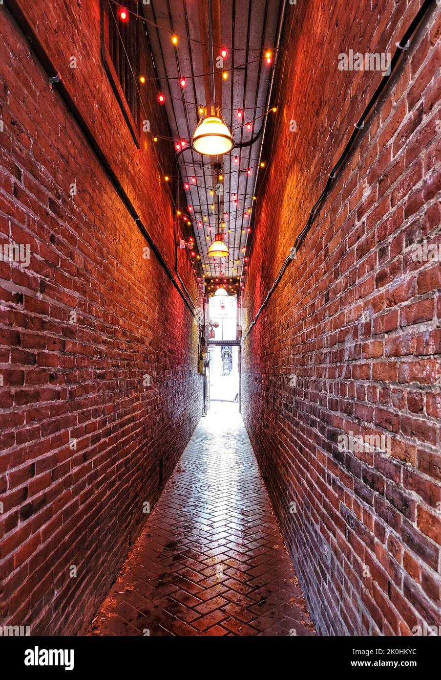 The colorful hanging lanterns in narrow alley between brick buildings ...