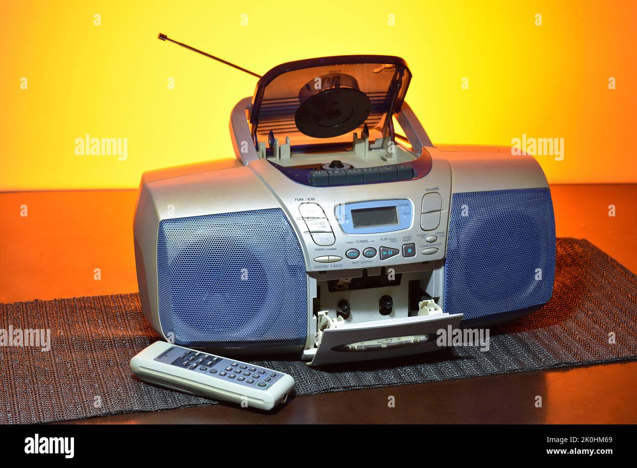 A CD music player and cassette on a table with an orange light in the ...
