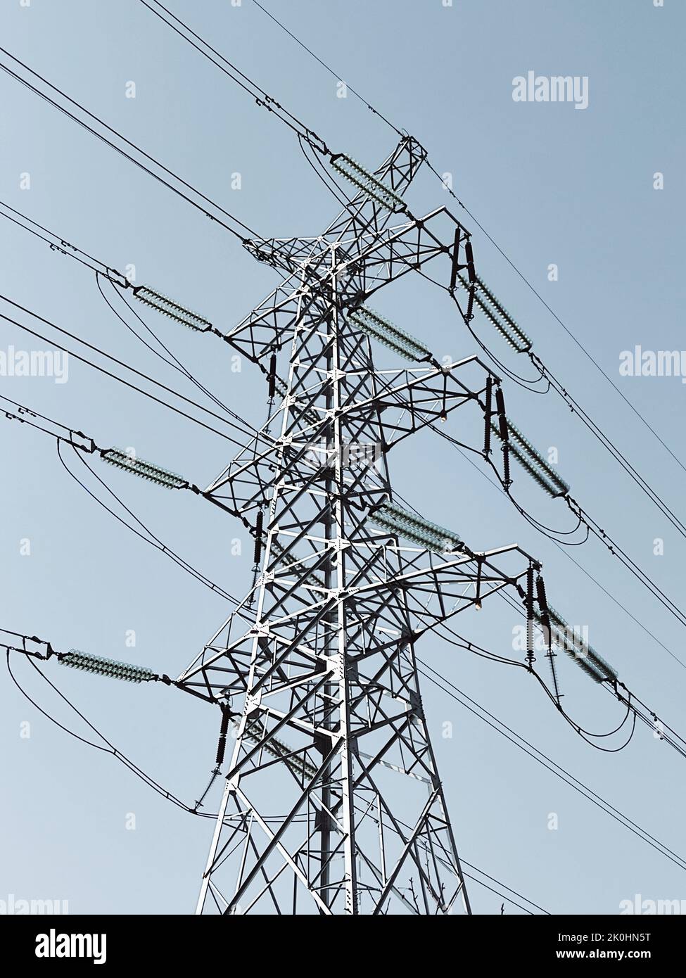 A low-angle shot of a power line column under a clear blue sky Stock ...