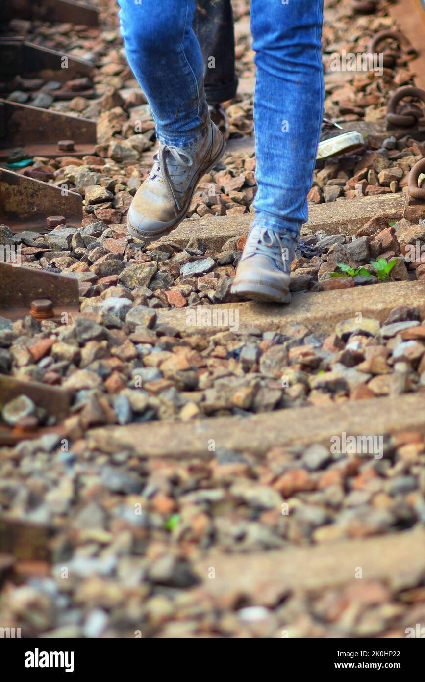 A vertical shot of male feet walking on the railway tracks Stock Photo ...