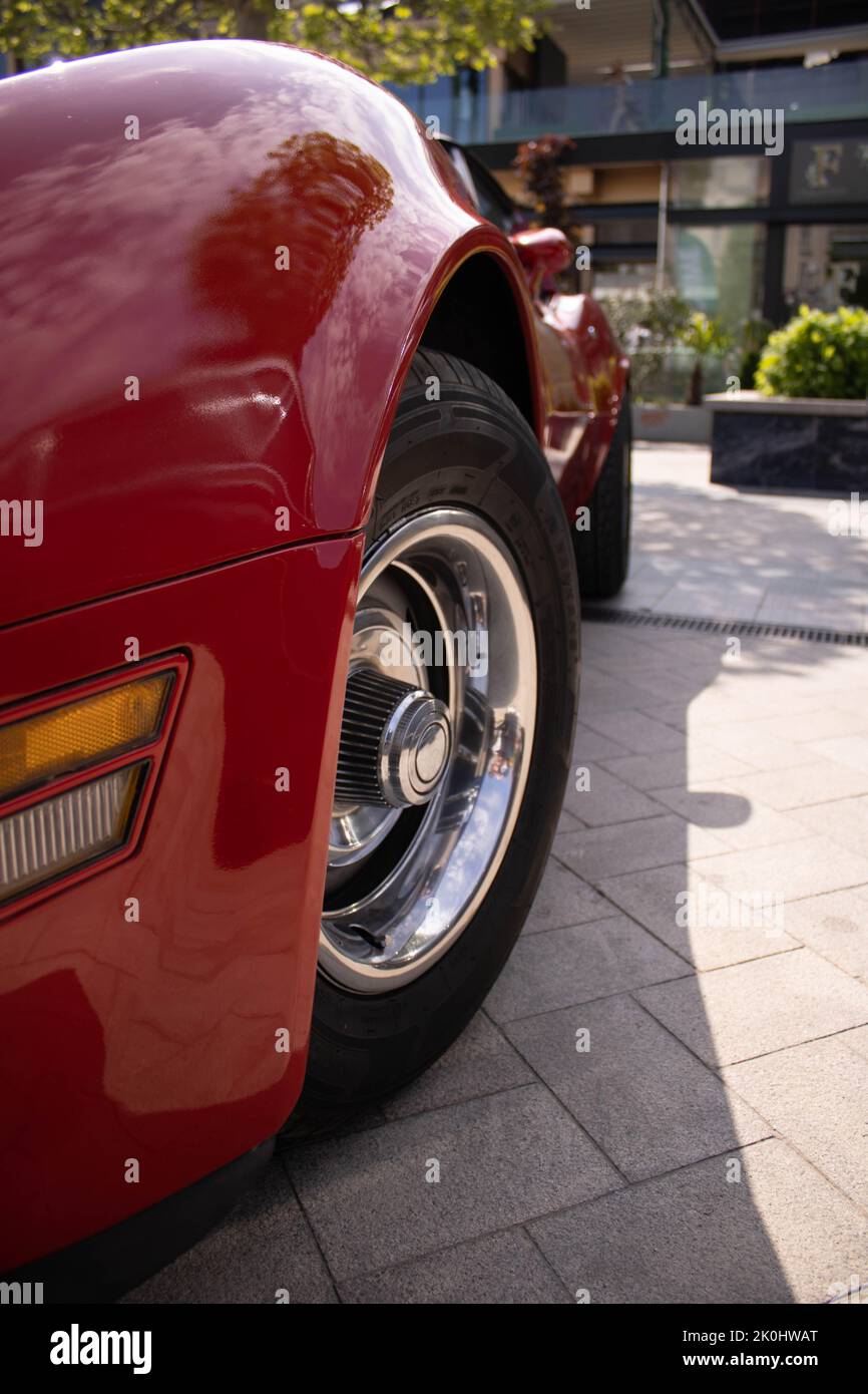 A vertical view of the rim of a classic American red muscle car parked ...