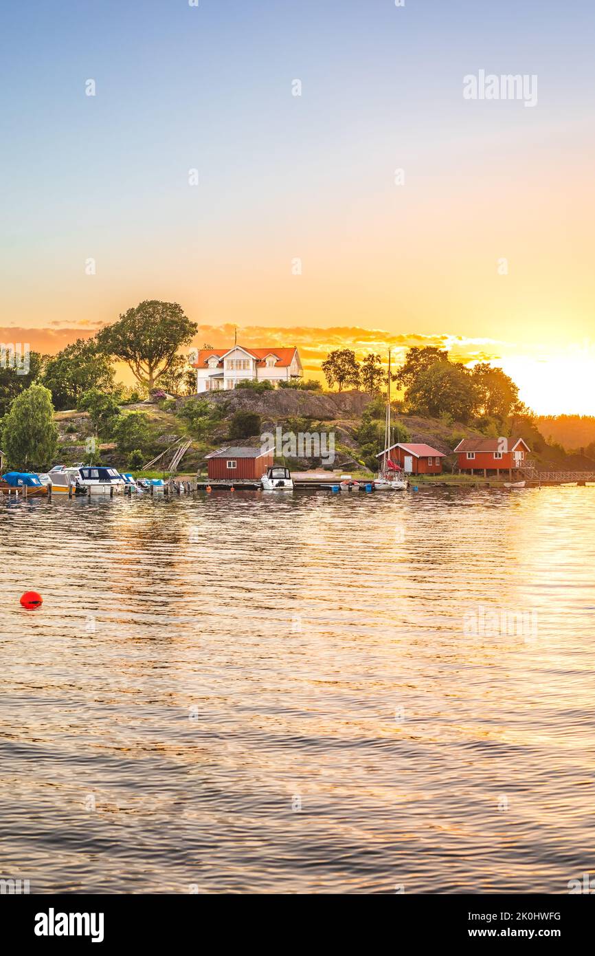 A small cottages with boats in the river at sunset in Henan, Orust ...