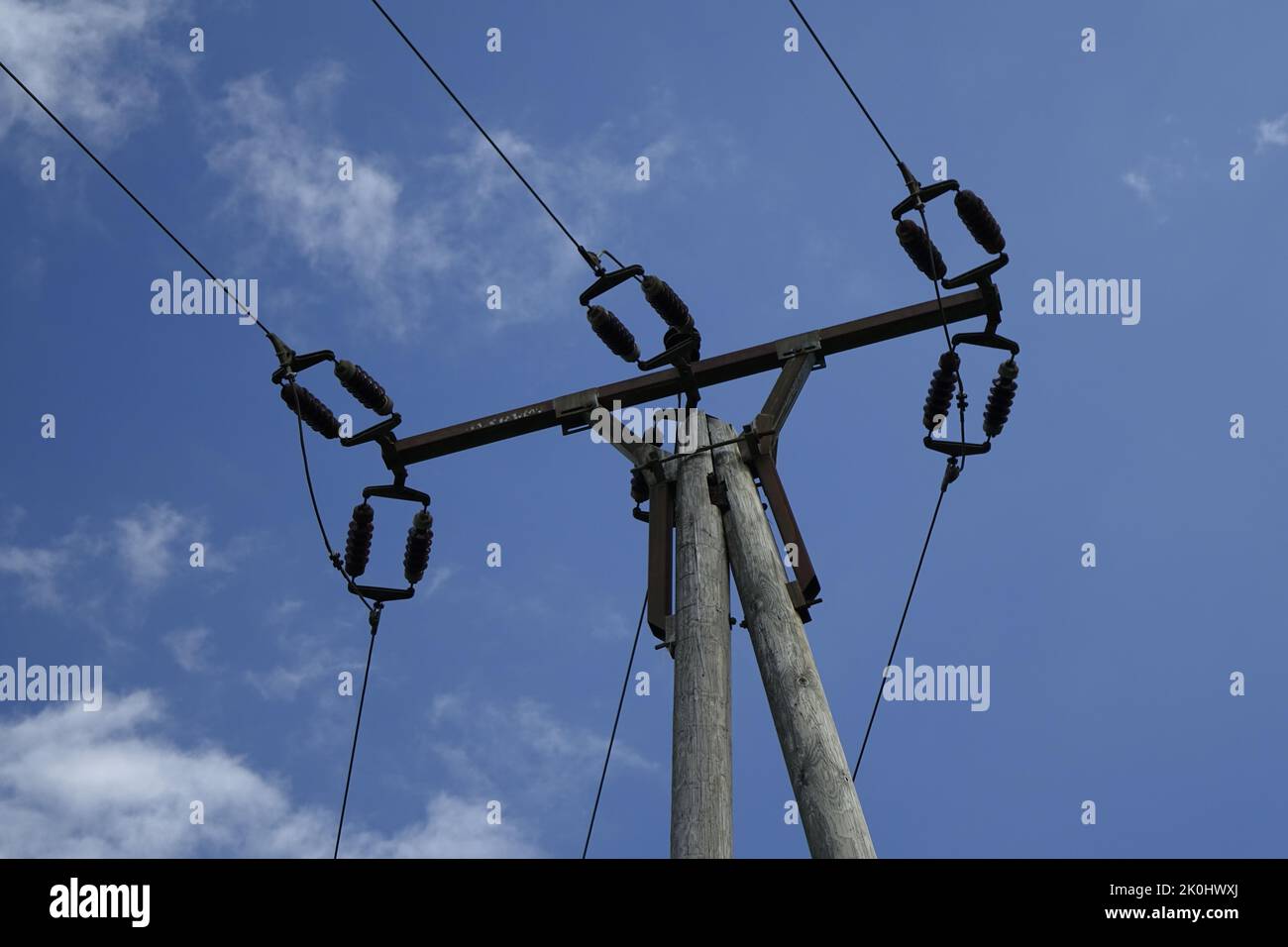 A low angle of a metallic utility pole against a blue sky in ...