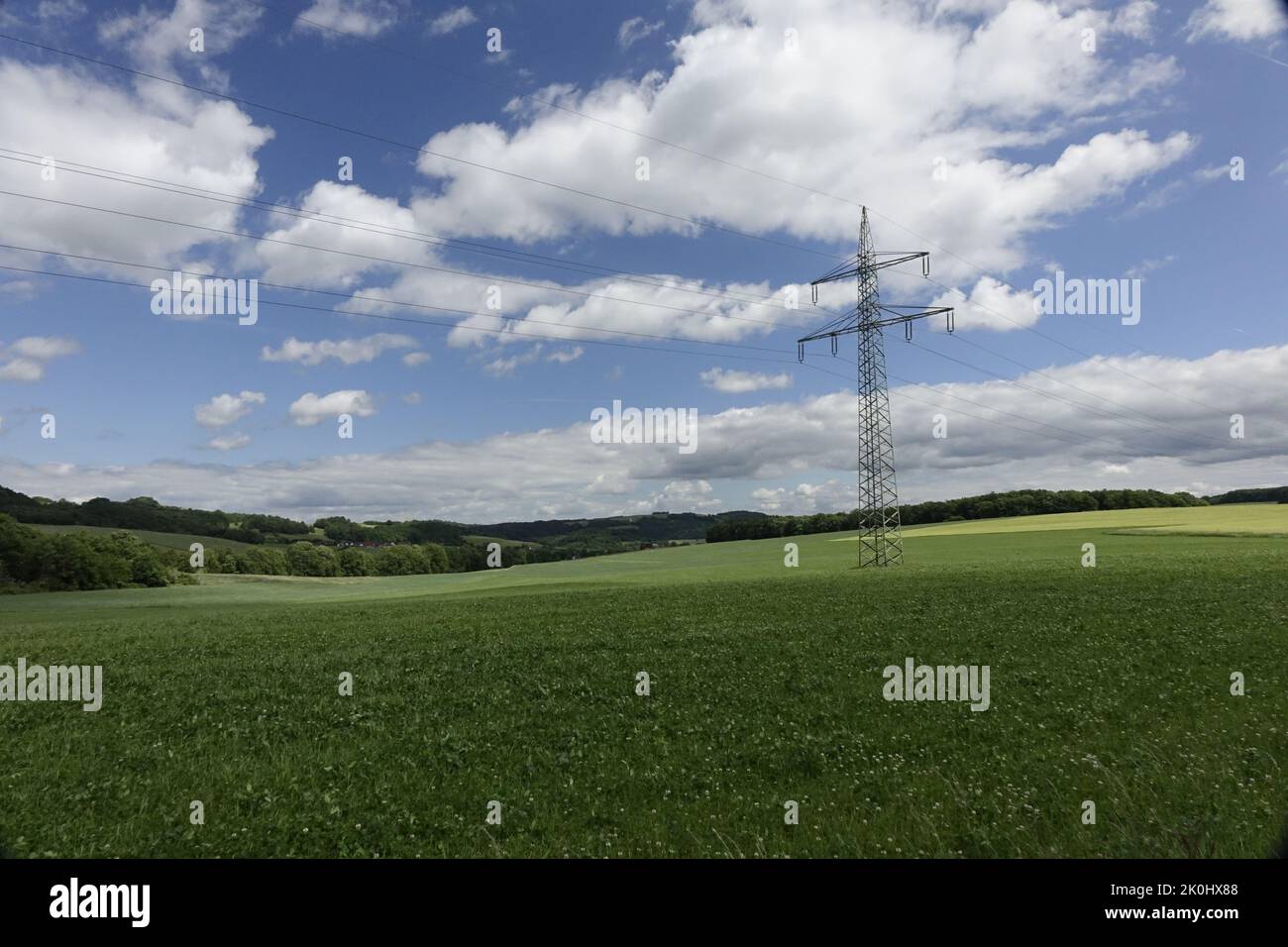 A scenic view of a utility pole in green field in sunlight in Korborn ...
