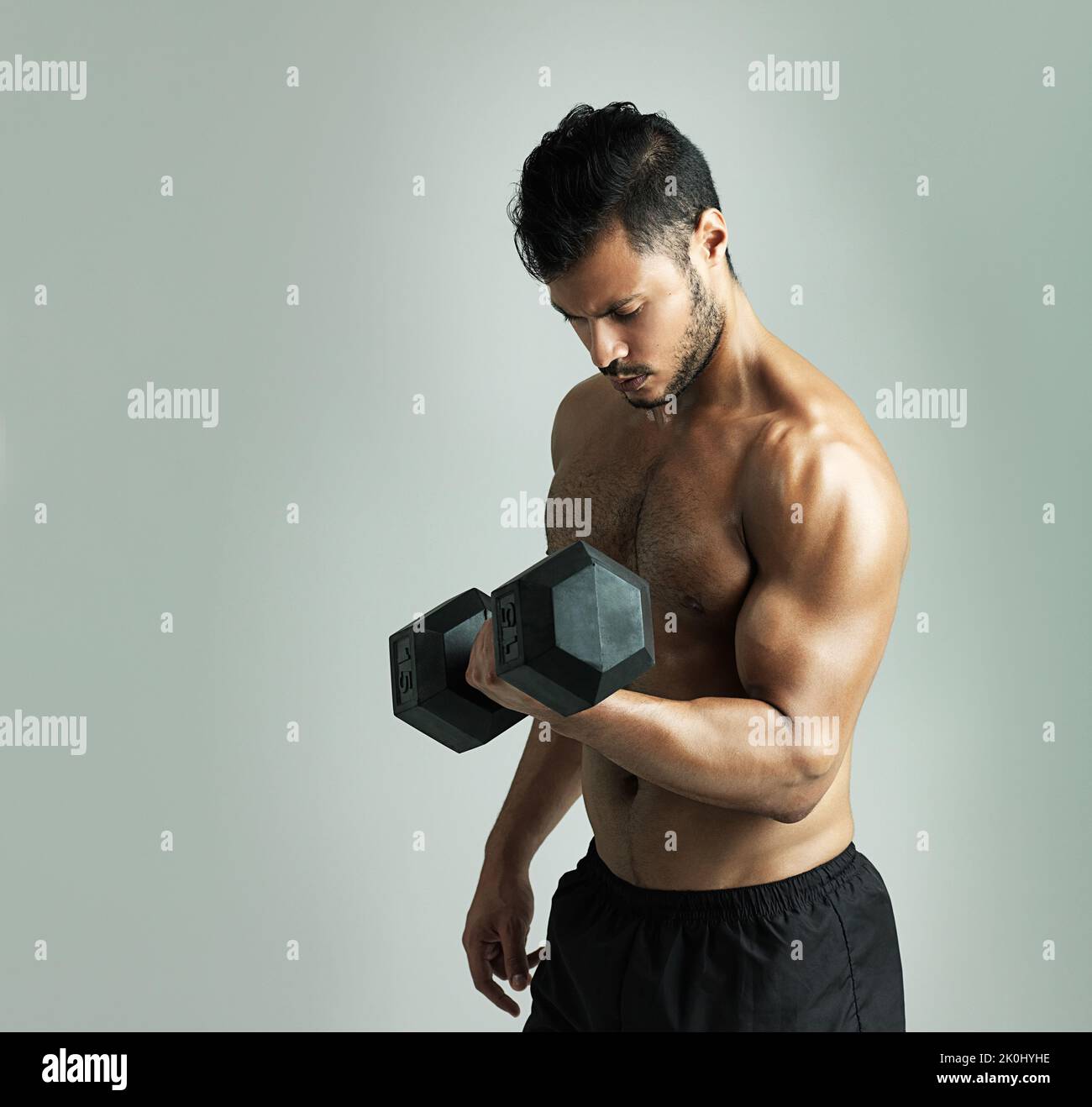 Perfecting his form. Studio shot of a young man working out with a ...