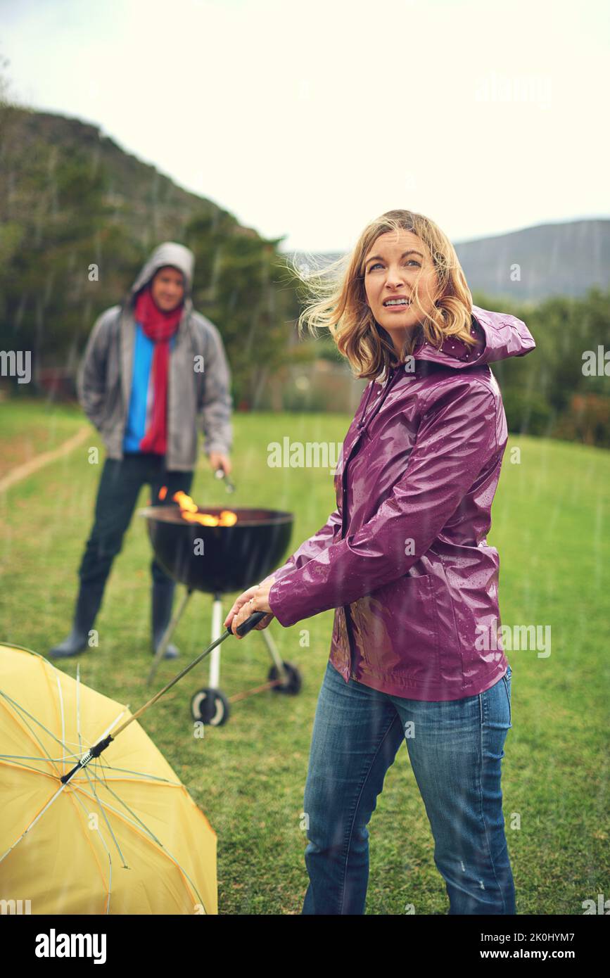 The sun will come out any moment now. a couple trying to barbecue in ...