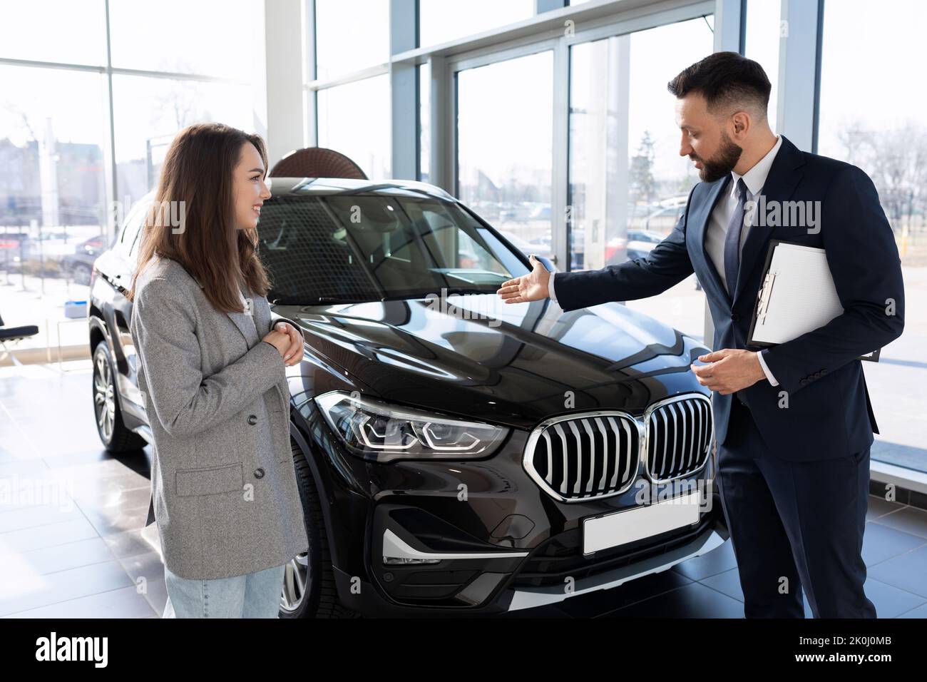 a salesman in a car dealership talks about the benefits of a new SUV to ...