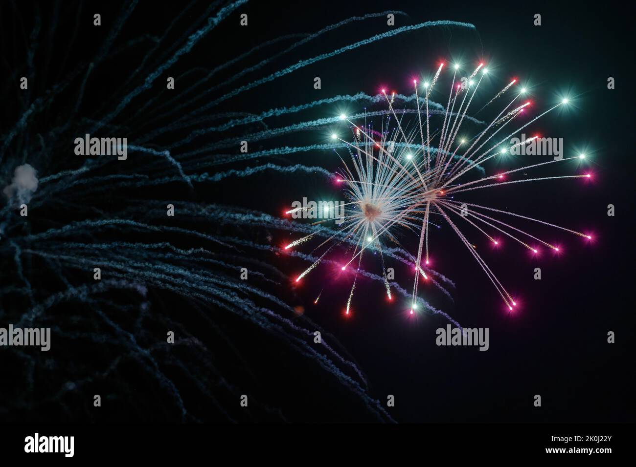 A burst of red and turquoise fireworks in the night sky Stock Photo - Alamy
