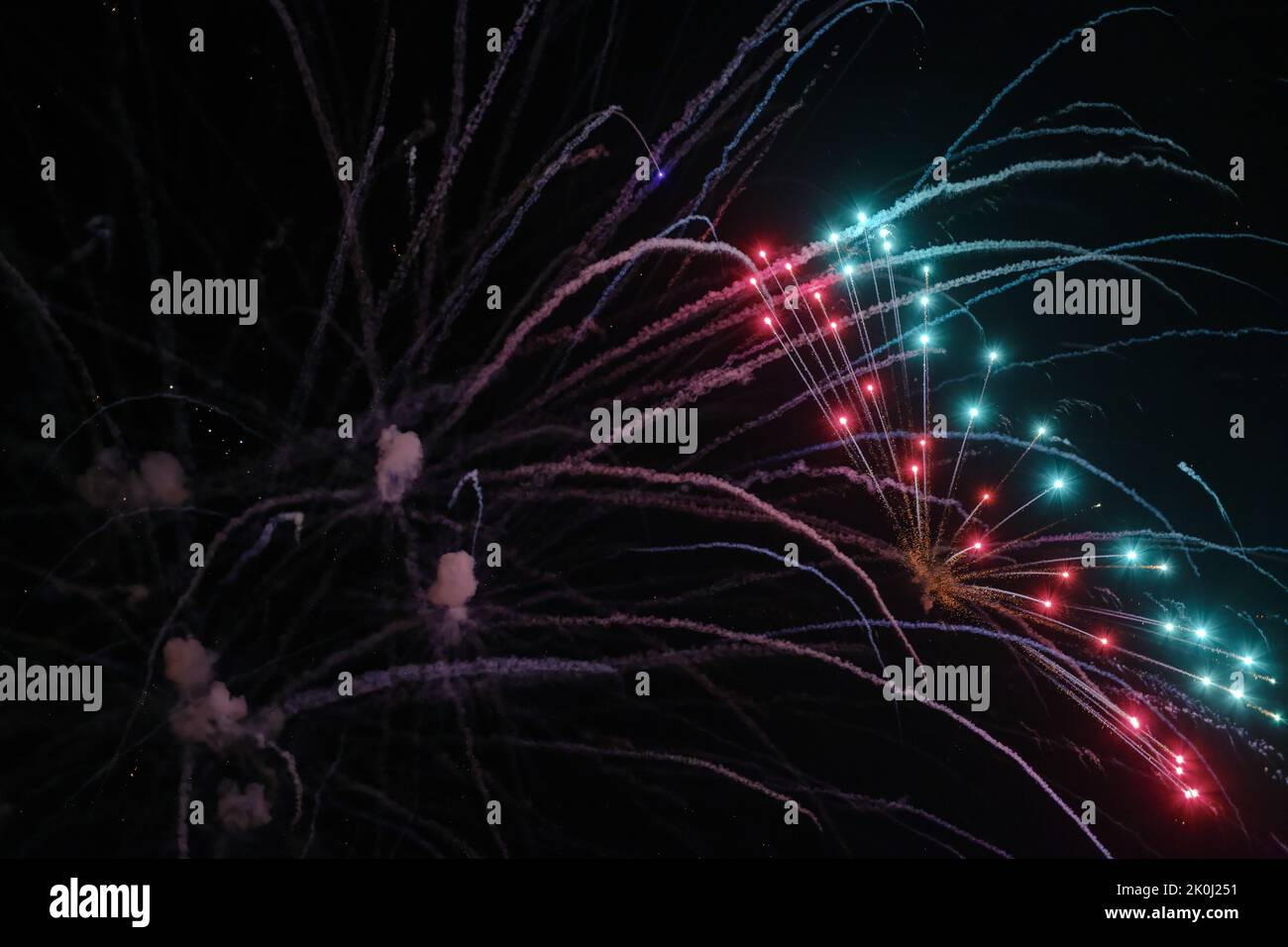 A burst of red and turquoise fireworks in the night sky Stock Photo - Alamy
