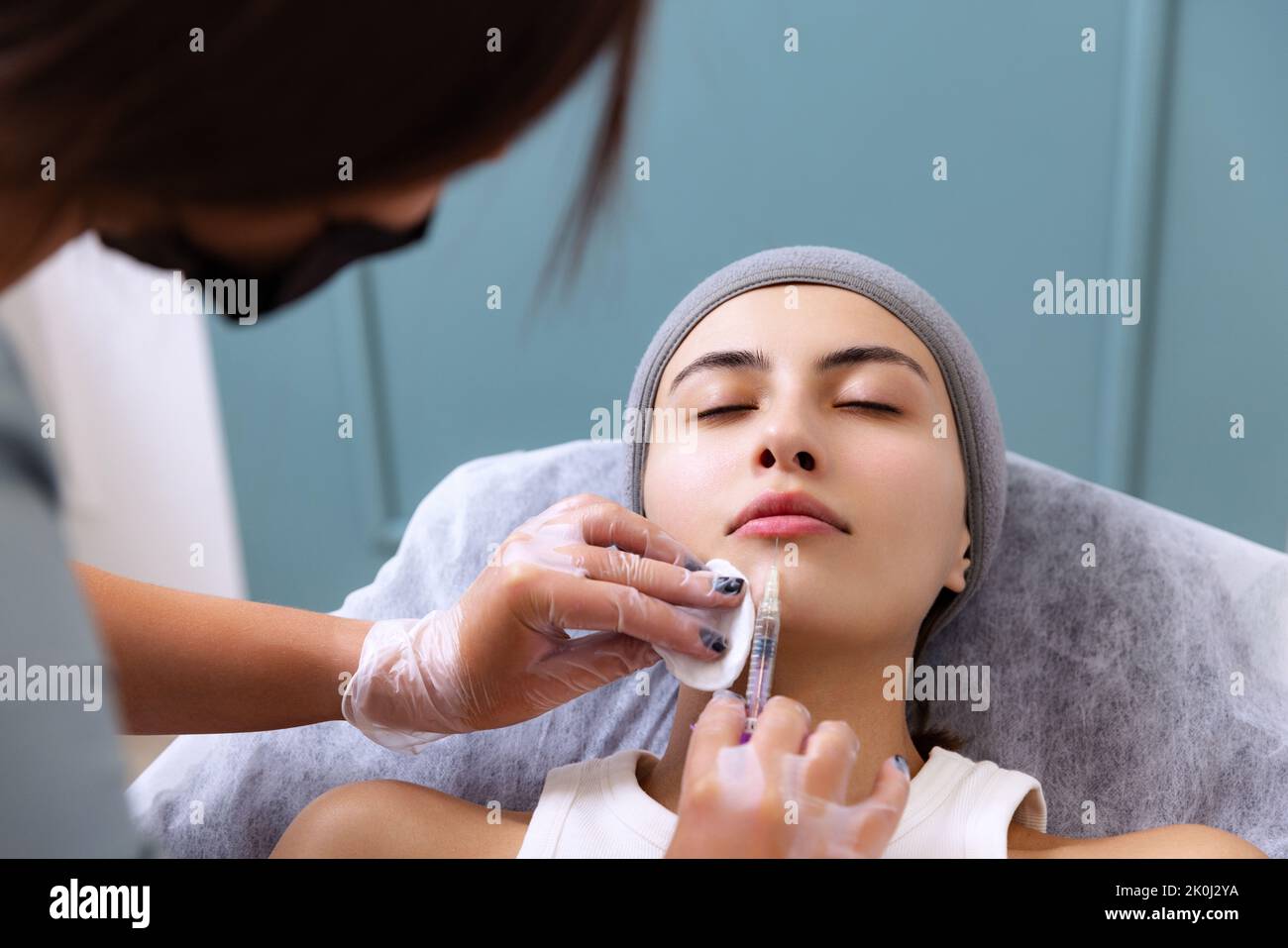 Female doctor hand in gloves lifting collagen in woman's lip area ...