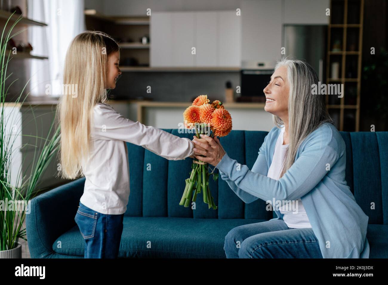Smiling caucasian little granddaughter gives bouquet of flowers to old ...