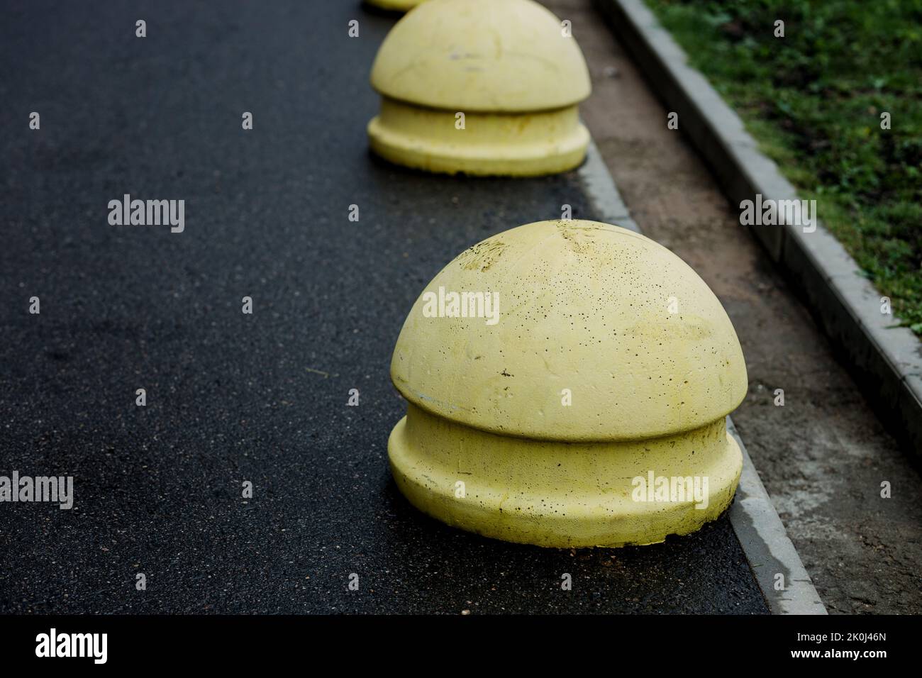 Concrete yellow ball spheres bollard on the corner of the road near the entrance. Parking street ...