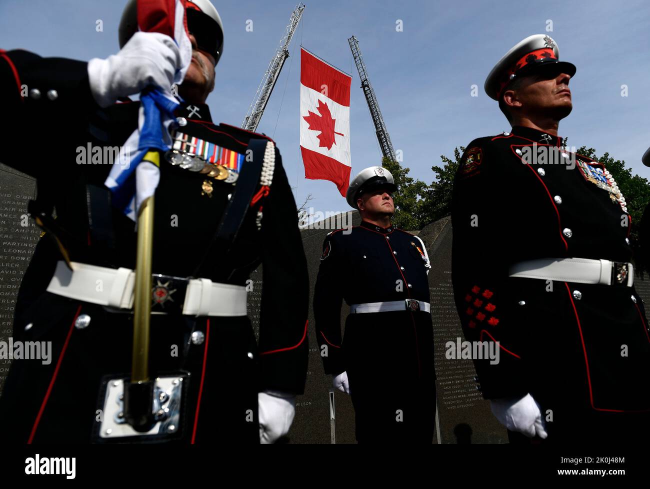 The honour guard stands in front of a giant Canadian flag flown from ...