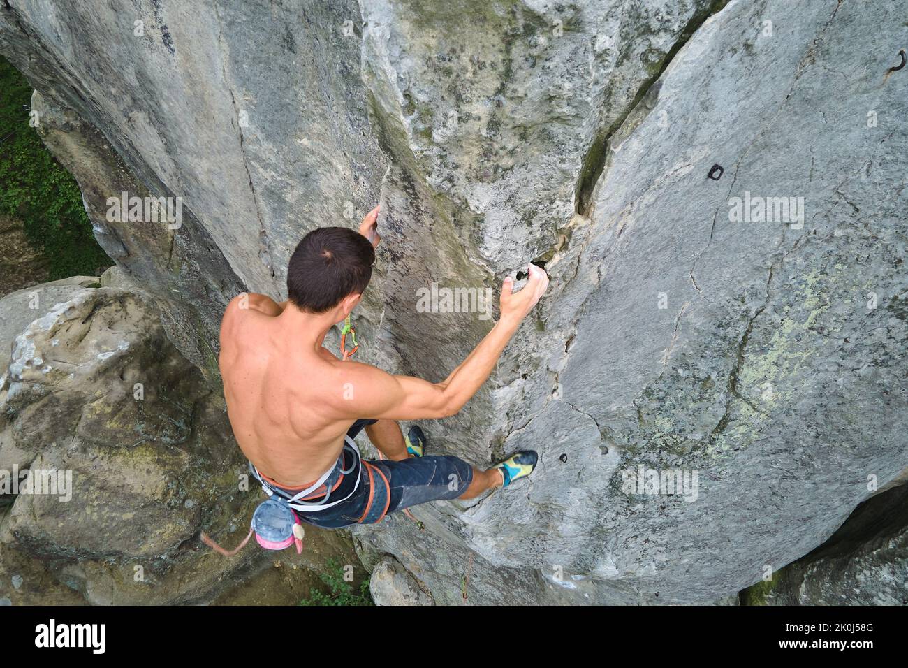 Strong male climber climbing steep wall of rocky mountain. Sportsman ...