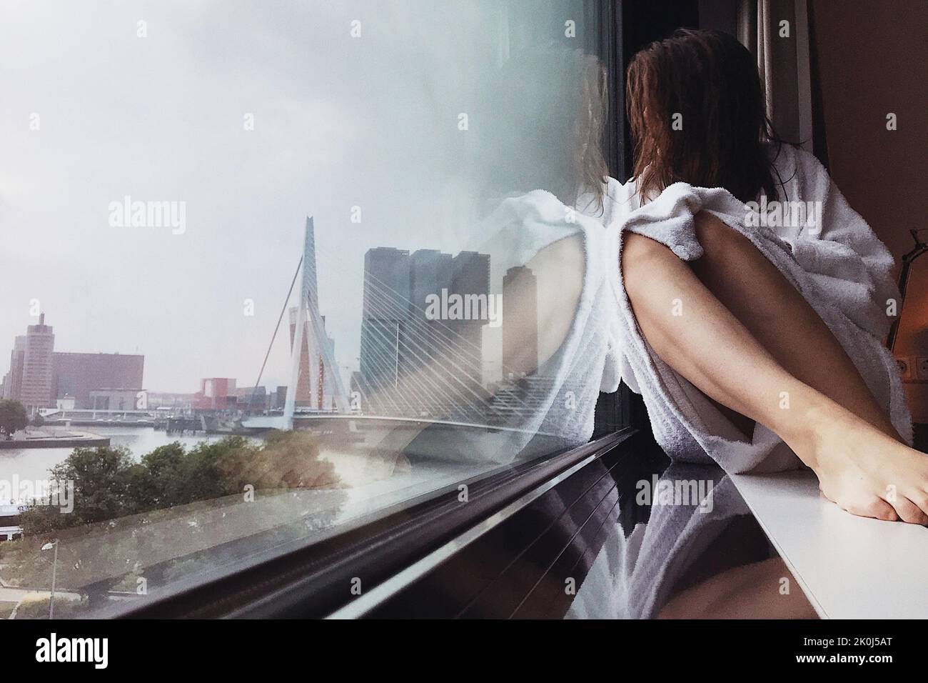 Girl sitting in a window with the skyline of Rotterdam Stock Photo - Alamy
