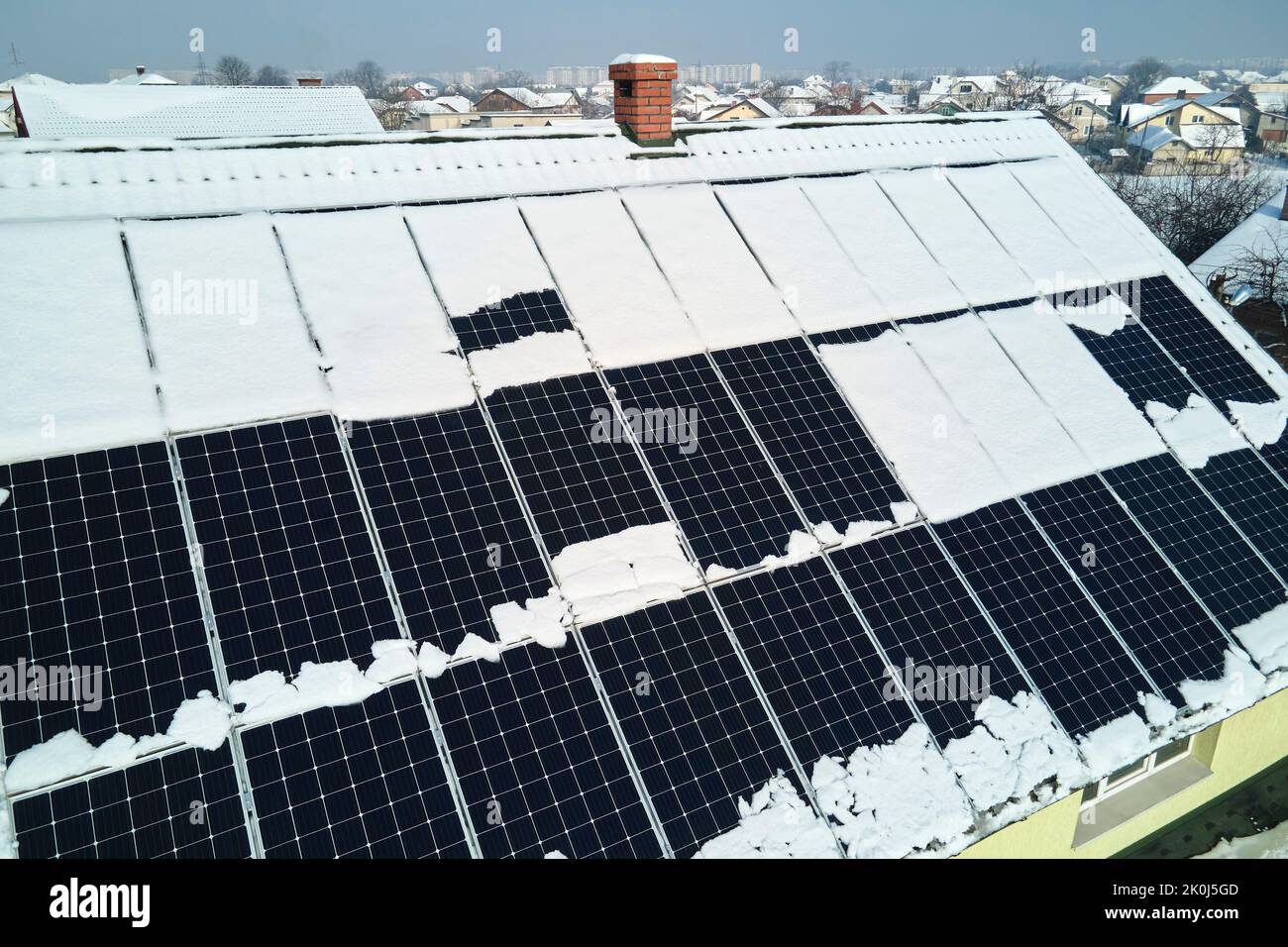 Aerial view of house roof with solar panels covered with snow melting ...