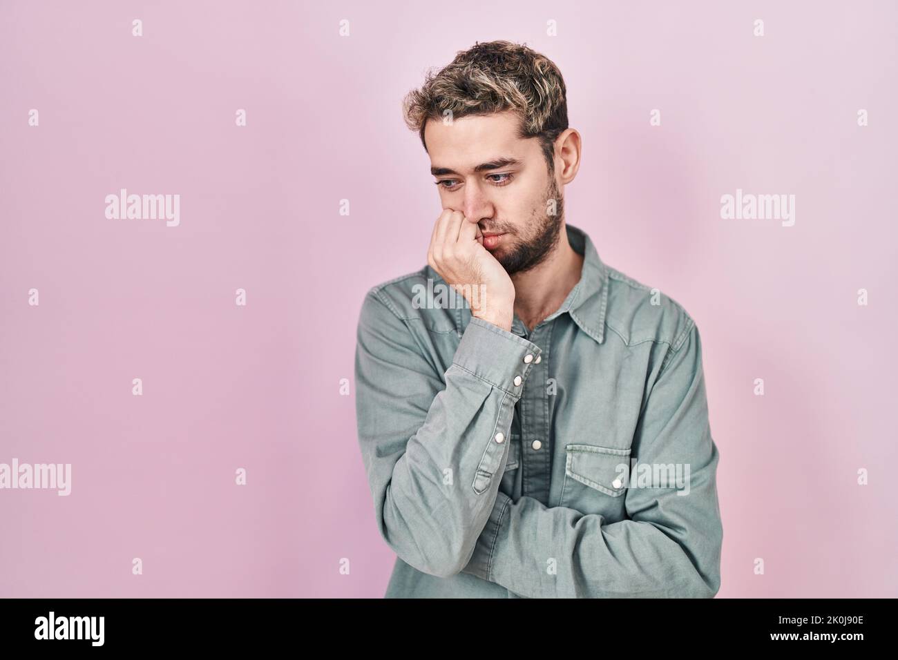 Hispanic man with beard standing over pink background thinking looking ...