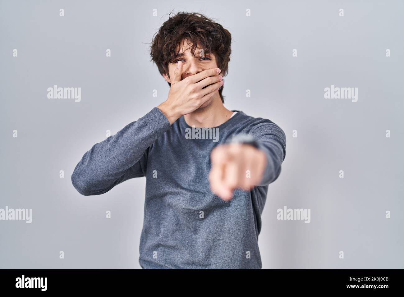Young man standing over isolated background laughing at you, pointing ...