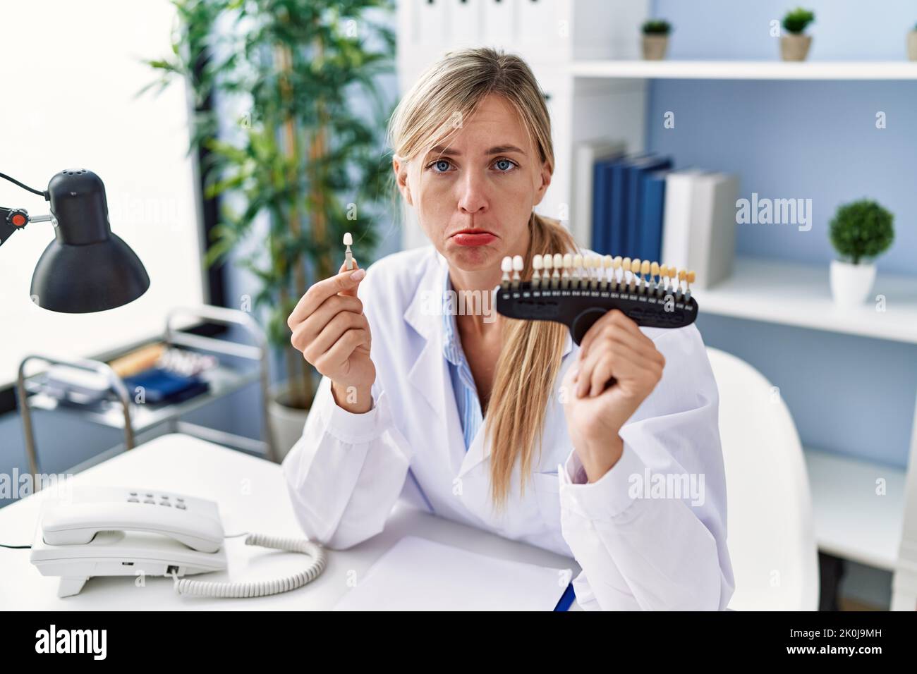 Beautiful dentist woman comparing teeth whitening depressed and worry ...